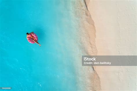 여름의 석양에 파도와 맑은 푸른 바다에서 도넛 수영 반지와 수영 하는 젊은 여자의 공중 보기 소녀 푸른 물 모래 해변과 열 대 공중 풍경입니다 평면도 여행 경관에 대한 스톡