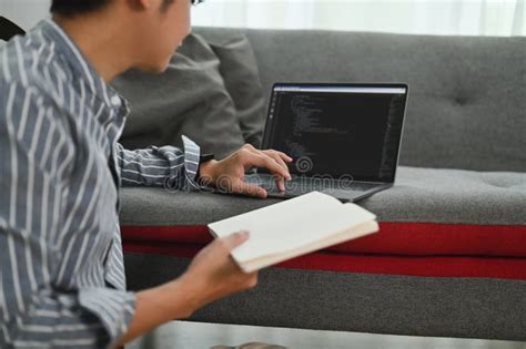 Male Programmer Sitting On Floor In Living Room Working On Laptop