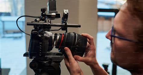 초점을 조정하고 새로운 광고의 촬영을 준비하는 동안 비디오 카메라 렌즈를 돌리는 젊은 카메라맨의 손 사진 Unsplash의 설비 이미지
