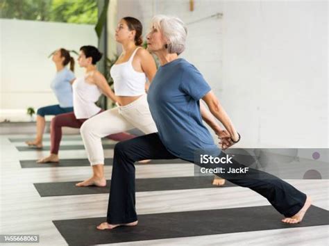 요가 스튜디오에서 몸의 유연성을 위해 스트레칭 운동을 하는 성인 그룹과 함께 있는 여성 20 24세에 대한 스톡 사진 및 기타