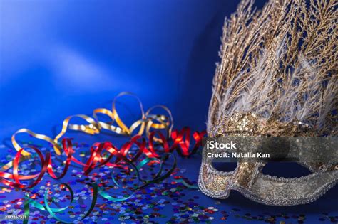 황금 마디 그라 또는 카니발 얼굴 마스크 색이 칠해진 반짝이와 색종이 조각이 있는 파란색 배경에 깃털이 있습니다 선택적 초점 베니스 카니발 0명에 대한 스톡 사진 및 기타