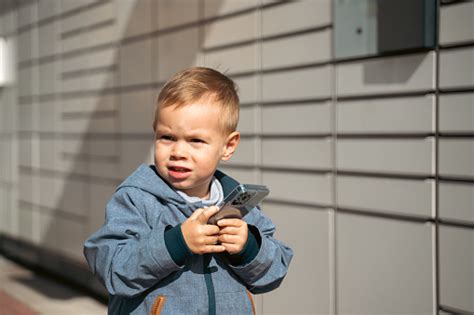 소포 사물함 근처에 휴대 전화를 들고있는 소년 쇼핑 사물함에서 소포를 수집합니다 휴대 전화의 어린이 스칸 Qr 코드 바코드 리더 현대 배송 개념과 휴대 전화 셀프 서비스