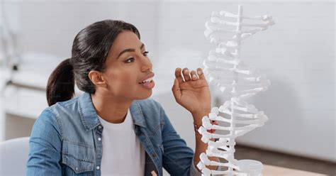 유전 연구 똑똑한 진지한 젊은 여성이 테이블에 앉아 유전학을 연구하는 동안 Dna 모델을 보고 있다 사진 Unsplash의 클로즈업 이미지