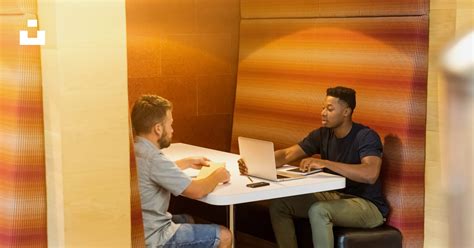 검은 가죽 벤치에 앉아있는 남자가 흰색 나무 테이블 위에 회색 노트북 컴퓨터를 들고 있습니다 사진 Unsplash의 무료 사업 이미지