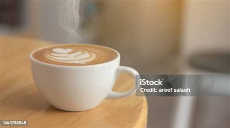 카페의 테이블에 서 있는 나무 배경에 예술 라떼의 흰색 컵 컵 위에 거품 꽃 작은 숟가락과 접시 나무 테이블에 커피 컵을 닫습니다 0명에 대한 스톡 사진 및 기타 이미지