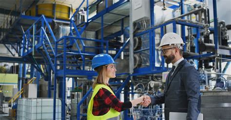 제복을 입은 엔지니어와 산업 노동자가 대형 금속 공장 홀에서 악수하고 이야기를 나누고 있다 사진 Unsplash의 공장 이미지