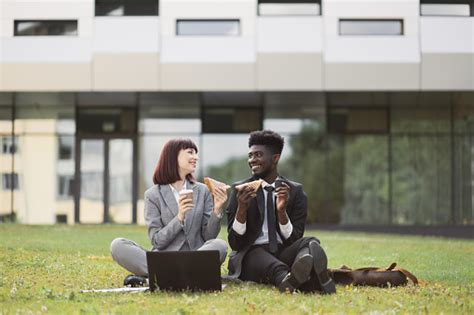 사무실 밖에서 잔디에 앉아 점심 식사 중에 샌드위치를 먹는 다민족 비즈니스 동료 점심에 대한 스톡 사진 및 기타 이미지 점심 야외 동료 Istock