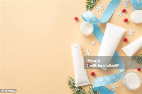 겨울 시즌 스킨케어 제품 개념 흰색 화장품 병의 상위 뷰 사진 서리 블루 곱슬 리본 마가목 열매와 눈송이 복사 공간이 있는 격리된 베이지색 배경에 12월에 대한 스톡 사진
