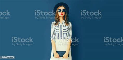흰색 줄무늬 셔츠 검은 둥근 모자 진한 파란색 배경에 핸드백 클러치를 착용 한 전체 길이 아름다운 젊은 여성 패션모델에 대한 스톡 사진 및 기타 이미지 Istock