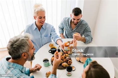 실내에서 함께 식사하는 행복한 가족 아침 식사 중에 식탁에 앉아 웃는 세대 가족 거실에서 함께 식사를 즐기는 행복한 쾌활한 가족 4 명에 대한 스톡 사진 및 기타 이미지