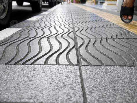 Low Angle Perspective View Of Pedestrian Walking With Yellow Blind Guide Tactile Paving For