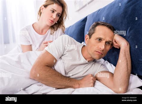 Portrait Of Upset Man Lying In Bed With Wife Behind Stock Photo Alamy