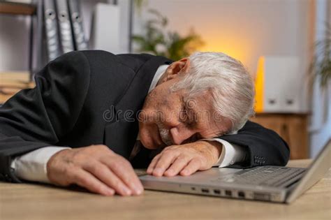 Bored Sleepy Senior Businessman Working On Laptop Leaning On Hand Falling Asleep At Office Desk