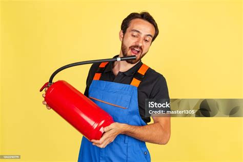 미소 짓는 젊은 수염을 기르는 남자 남성 자동차 정비사 또는 파란색 작업을 입은 피터의 반 길이 초상화가 노란색 스튜디오 배경에