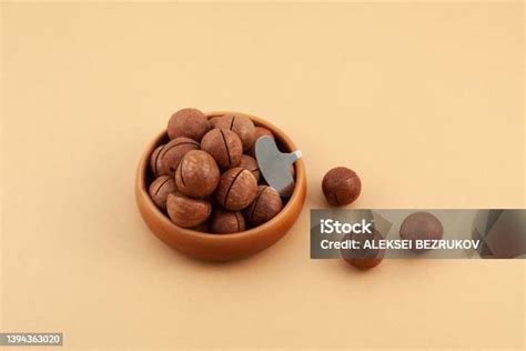 베이지 색 배경에 찰흙 그릇에 마카다미아 견과류 상단보기 마카다미아는 딱딱한 껍질을 가진 맛있는 너트입니다 0명에 대한 스톡 사진 및 기타 이미지 Istock