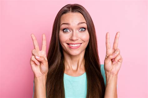 재미 있는 여학생의 사진 초상화 양손으로 V 기호를 보여주고 미소 짓고 파스텔 핑크 컬러 배경에 고립 된 응시 갈색 머리에 대한