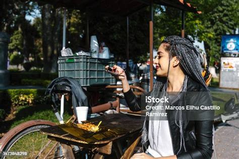 멕시코 시티의 공원에서 멕시코 타말레 길거리 음식을 먹는 머리띠 머리를 가진 젊은 라틴 여성 히스패닉 사람들 땋은 머리에 대한 스톡 사진 및 기타 이미지 Istock