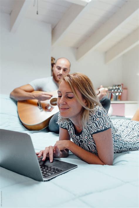Adult Couple Spending Time In Their Bedroom Using A Laptop And Playing