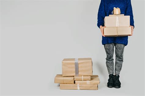 메리 크리스마스 카드 휴 년 크리스마스 생일 배너 회색 중립 배경에 리본과 많은 공예 선물 상자를 들고 파란색 스웨터에 여자