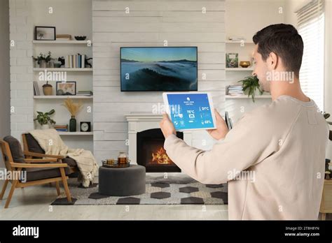 Man Using Smart Home Control System Via Application On Tablet Indoors
