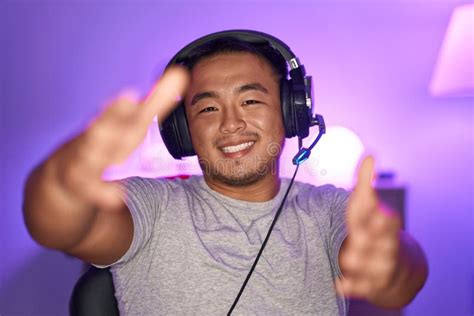 Chinese Young Man Playing Video Games Wearing Headphones Looking At The