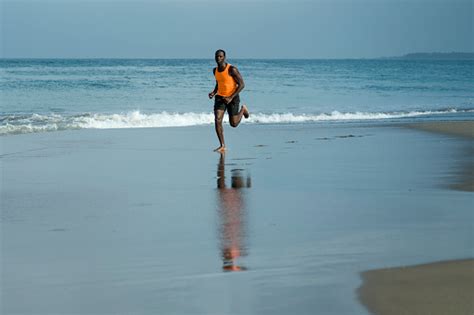 스포츠 운동과 건강한 라이프 스타일 개념에서 바다에서 여름 피트니스 조깅 운동을하고 해변에서 달리는 젊은 매력적이고 맞는 흑인 미국인의 운동 전신 초상화 건강한 생활방식에