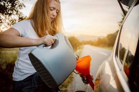 도로에 있는 한 여성이 깨진 차를 고치려고 합니다 여자는 여행을 계속하려고 그녀의 차에 가솔린을 부어 자동차 옆에 가솔린 양동이를 가진 여성 30 34세에 대한 스톡 사진