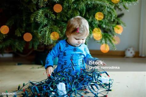 크리스마스 트리에서 휴일 장식을 복용 귀여운 아기 소녀 가벼운 화환을 들고 있는 아이 축하 후 가족 제거 및 나무를 폐기 12월에 대한 스톡 사진 및 기타 이미지 Istock