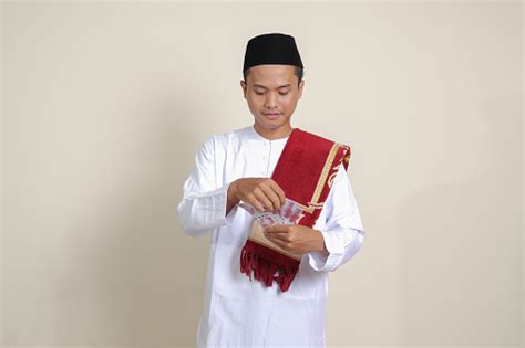 십만 루피아를 보여주는 흰 셔츠를 입은 매력적인 아시아 무슬림 남자의 초상화 금융 및 저축 개념 회색 배경에 격리된 이미지 20 24세에 대한 스톡 사진 및 기타 이미지