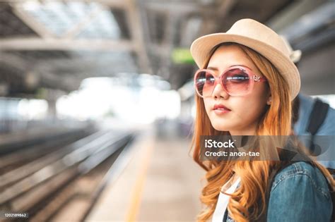 역에서 휴대 전화를 들고 휴가 시간에 기차를 기다리는 행복한 아시아 커플 여행자 배낭 기차와 젊은 아시아 관광객 관광 도시 태국