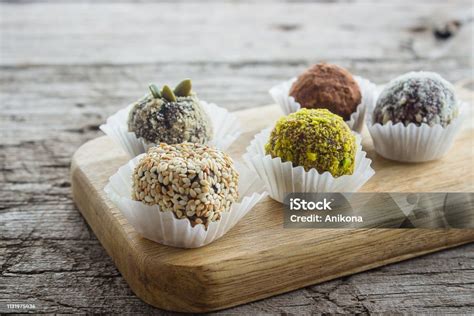 말린 과일과 견과류를 코코넛 칩 카 카오 아마 씨 피스타치오 참 깨로 만든 건강 한 에너지 볼 나무 보드에 원시 채식 사탕 공 스포츠 장비에 대한 스톡 사진 및 기타 이미지