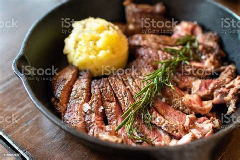 얇게 썬 갈비눈을 곁들인 주철 접시에 으깬 감자와 소스를 얹은 미디엄 레어 스테이크를 테이블 위에 놓습니다 갈비 음식에 대한 스톡 사진 및 기타 이미지 Istock