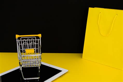 인터넷 개념으로 온라인 전자 상거래 및 쇼핑 흰색 디지털 태블릿과 노란색 쇼핑 백 작은 트롤리 텍스트 공간이 있는 소매 및 블랙 프라이데이 아이디어 Cyber Monday에