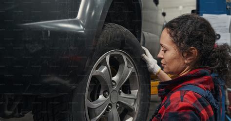 차고에서 자동차 바퀴를 검사하는 작업 장갑을 낀 여성 차량 기술자 사진 Unsplash의 우크라이나 이미지