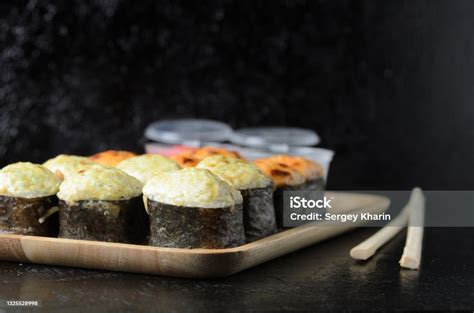 얇은 말린 바다 풀잎에 싸여 있는 해산물 쌀 롤 세트는 검은 나무 배경에 생강과 와사비를 곁들인 나무 접시에 싸여 있습니다 0