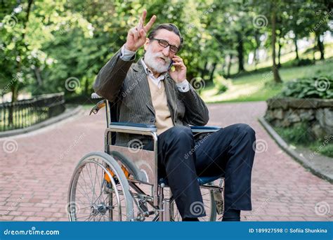 Happy Laughing Senior Handicapped Man In A Wheelchair Walking In A