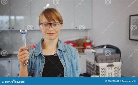 Young Woman With Safety Glasses Holding A Spanner Upwards In The