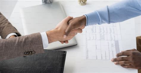 알아볼 수 없는 흑인이 서류를 들고 테이블에 앉아 상담 후 변호사와 악수하는 모습 사진 Unsplash의 핸드셰이크 이미지