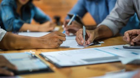 Group Of Colleagues Gathered Around A Conference Table To Review A Printed Questionnaire Quality