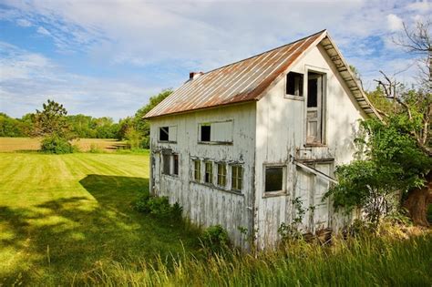 Premium Photo Abandoned Farm House In Field With Busted Windows And