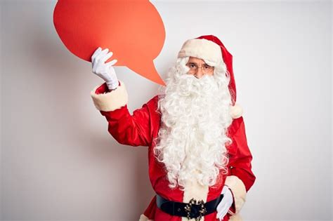 산타 의상을 입은 중년 남성이 고립된 흰색 배경 위에 연설 거품을 들고 스마트 한 얼굴에 자신감있는 표정을 지니고 심각한 생각을 하고 있습니다 기포에 대한 스톡 사진 및