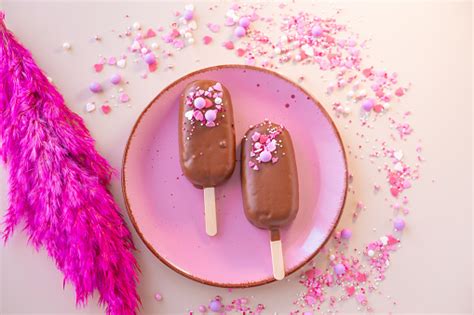 컵케이크 베이지 색 배경에 분홍색 수건이있는 분홍색 접시에 아이스크림 형태의 막대기에 초콜릿 비스킷 식욕을 돋우는 컵 케이크와 패스트리 쵸크 패스트리 0명에 대한 스톡 사진