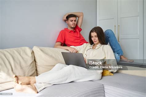 아름다운 젊은 커플 남자와 여자가 소파에 앉아있다 여자는 노트북에서 무언가를보고있다 남자는 그녀 뒤에있다 관계 부드러움 사랑