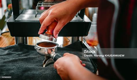 포터필터를 들고 있는 바리스타와 에스프레소 커피를 만드는 커피 탬퍼의 손 바리스타는 커피숍에서 탬퍼를 사용하여 분쇄 커피를