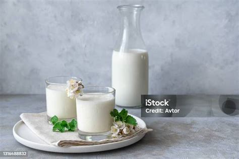 녹지와 꽃이 있는 회색 배경에 두 잔의 천연 건강한 우유 음료 요구르트 케피어 라시 라씨에 대한 스톡 사진 및 기타 이미지