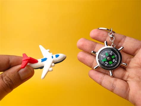 Premium Photo Hand Holding Toys Plane And Compass Keychain On A Yellow Backgroundholidays And