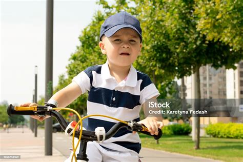 스포츠 개념입니다 자전거를 탄 소년 모자와 줄무늬 티셔츠를 입은 4 살짜리 작은 백인 소년이 여름에 자전거 도로를 따라 자전거를