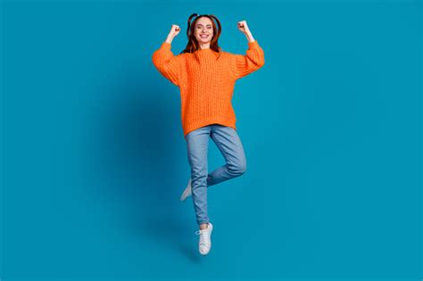 행운의 긍정적 인 소녀 입고 오렌지 스웨터 점프 높은 상승 주먹 빈 공간 외딴 파란색 배경 20 24세에 대한 스톡 사진 및 기타 이미지 20 24세 가을 계절