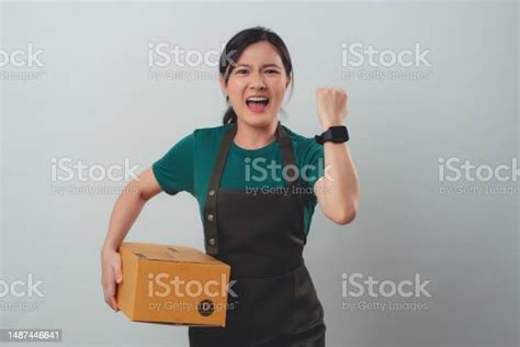 앞치마를 두른 아시아 여성은 시간을 확인하고 판지 상자를 들고 충격을 받고 배경 위에 고립되어 서 있다 걱정하는에 대한 스톡 사진 및 기타 이미지 Istock