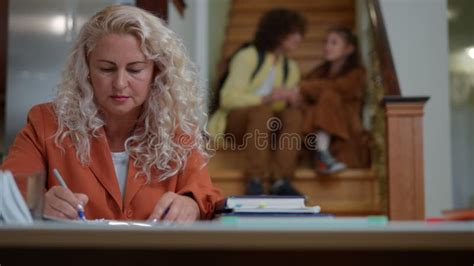 Positive Son And Daughter Talking Eating Breakfast As Blurred Busy Mother Walking With Paperwork